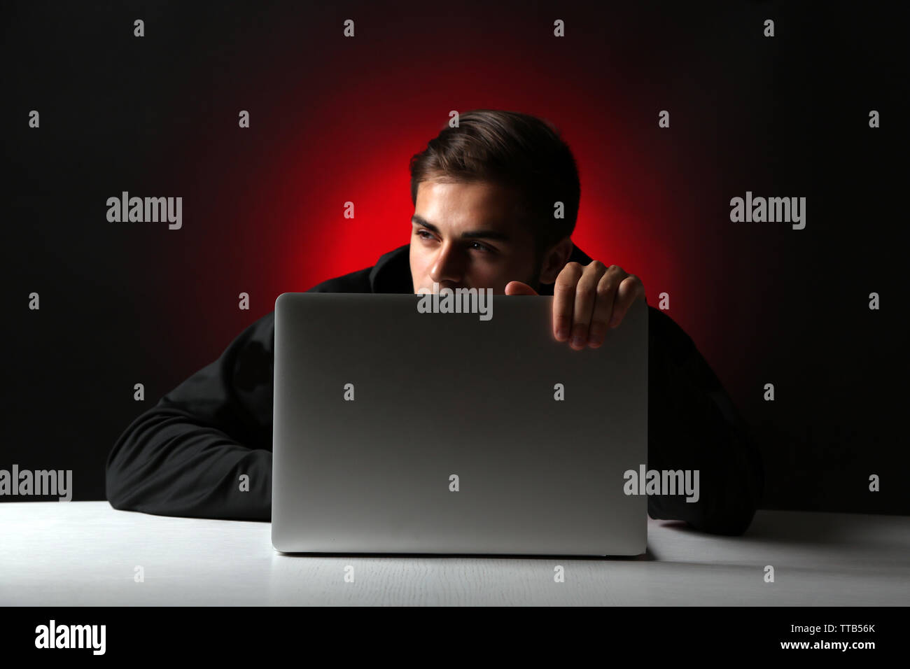 Hacker with computer and laptop on colorful dark background Stock Photo ...