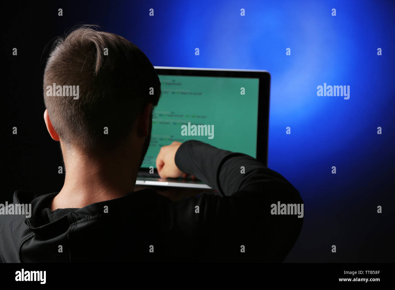 Hacker with computer and laptop on colorful dark background Stock Photo ...