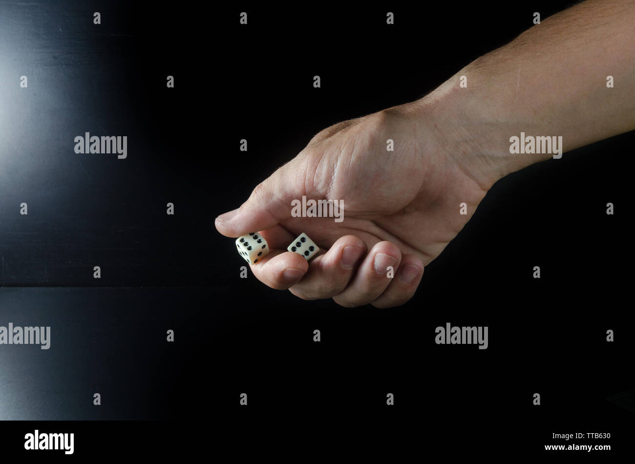 Male hand throwing dice on a black background Stock Photo - Alamy