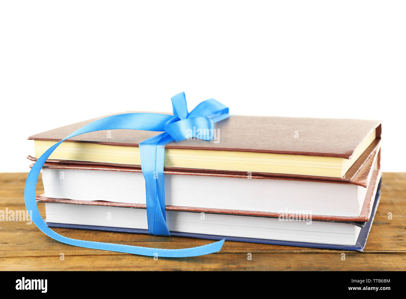 Stack of books with ribbon on table isolated on white Stock Photo - Alamy