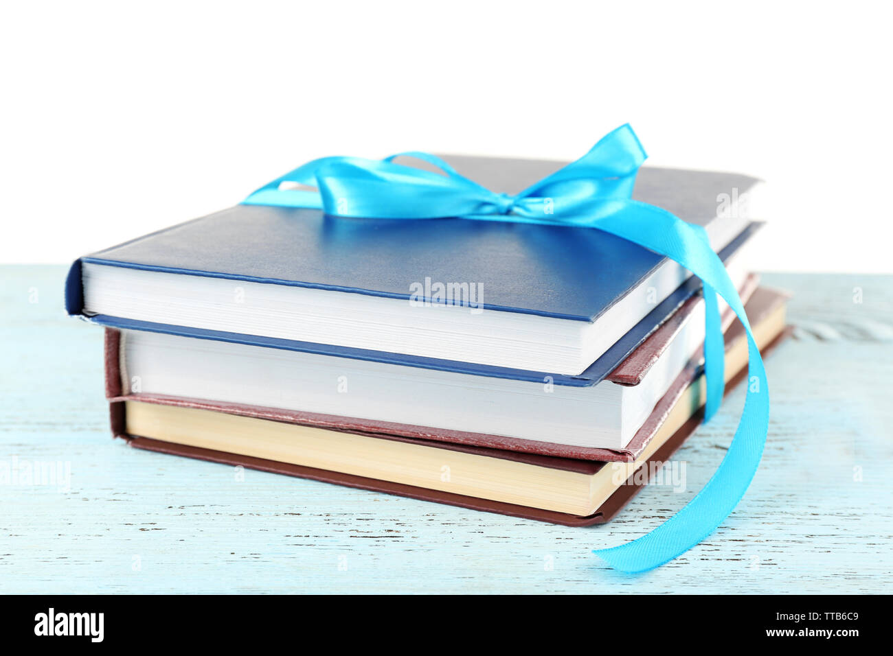 Stack of books with ribbon on table isolated on white Stock Photo - Alamy