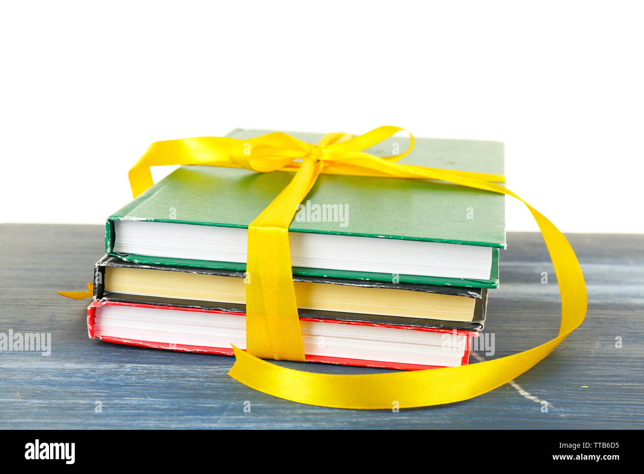 Stack of books with ribbon on table isolated on white Stock Photo - Alamy