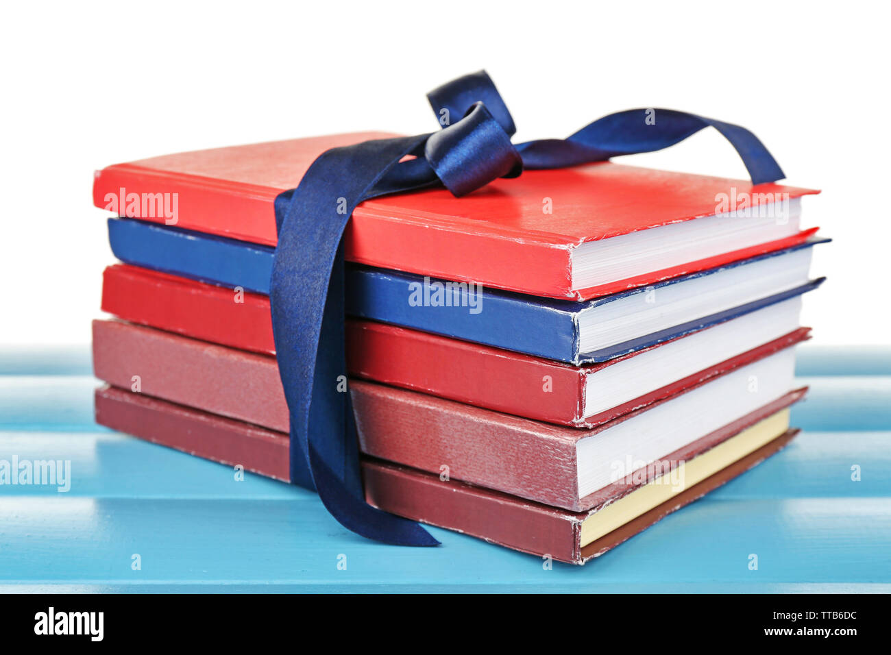 Stack of books with ribbon on light background Stock Photo - Alamy