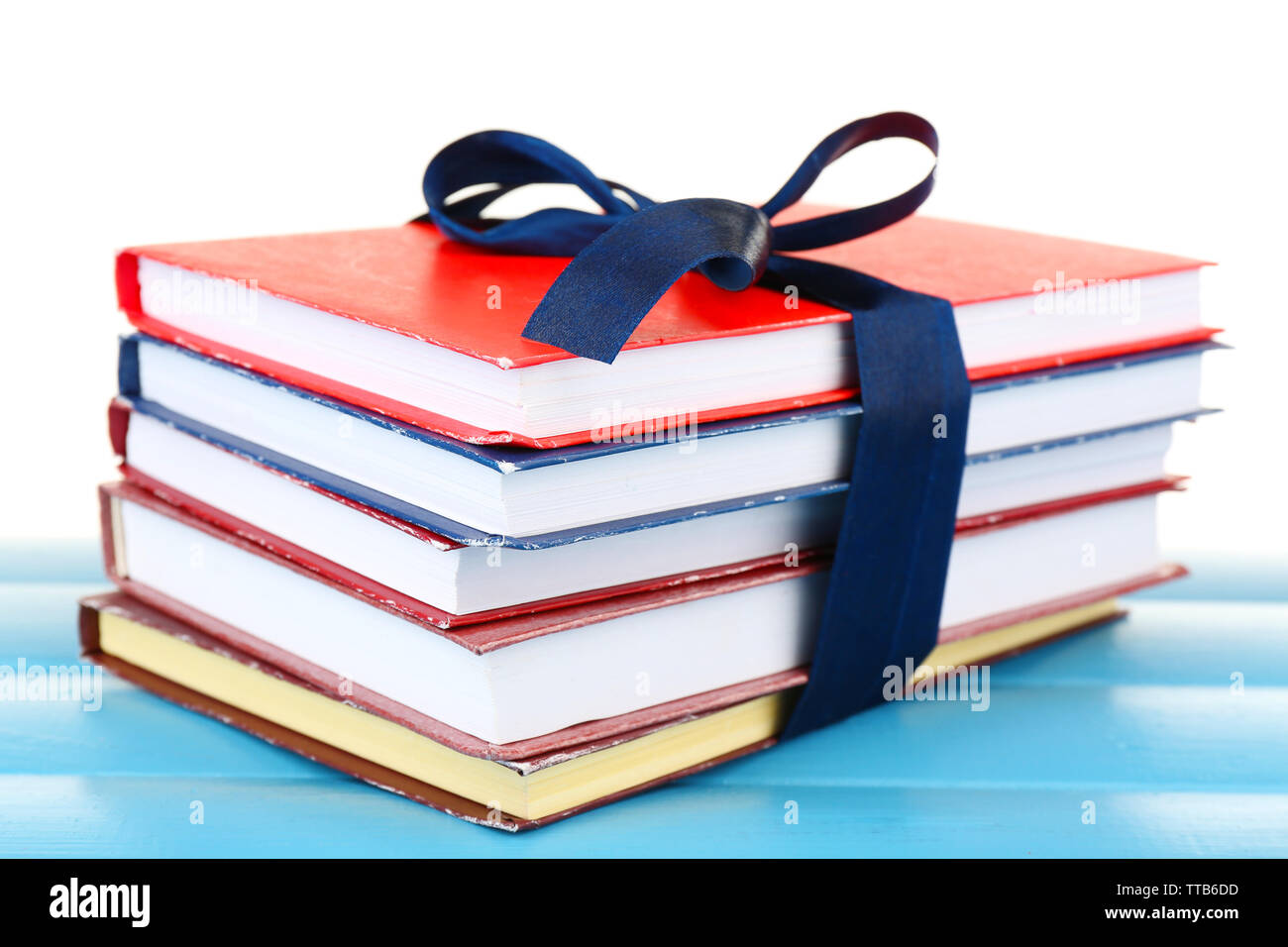Stack of books with ribbon on light background Stock Photo - Alamy