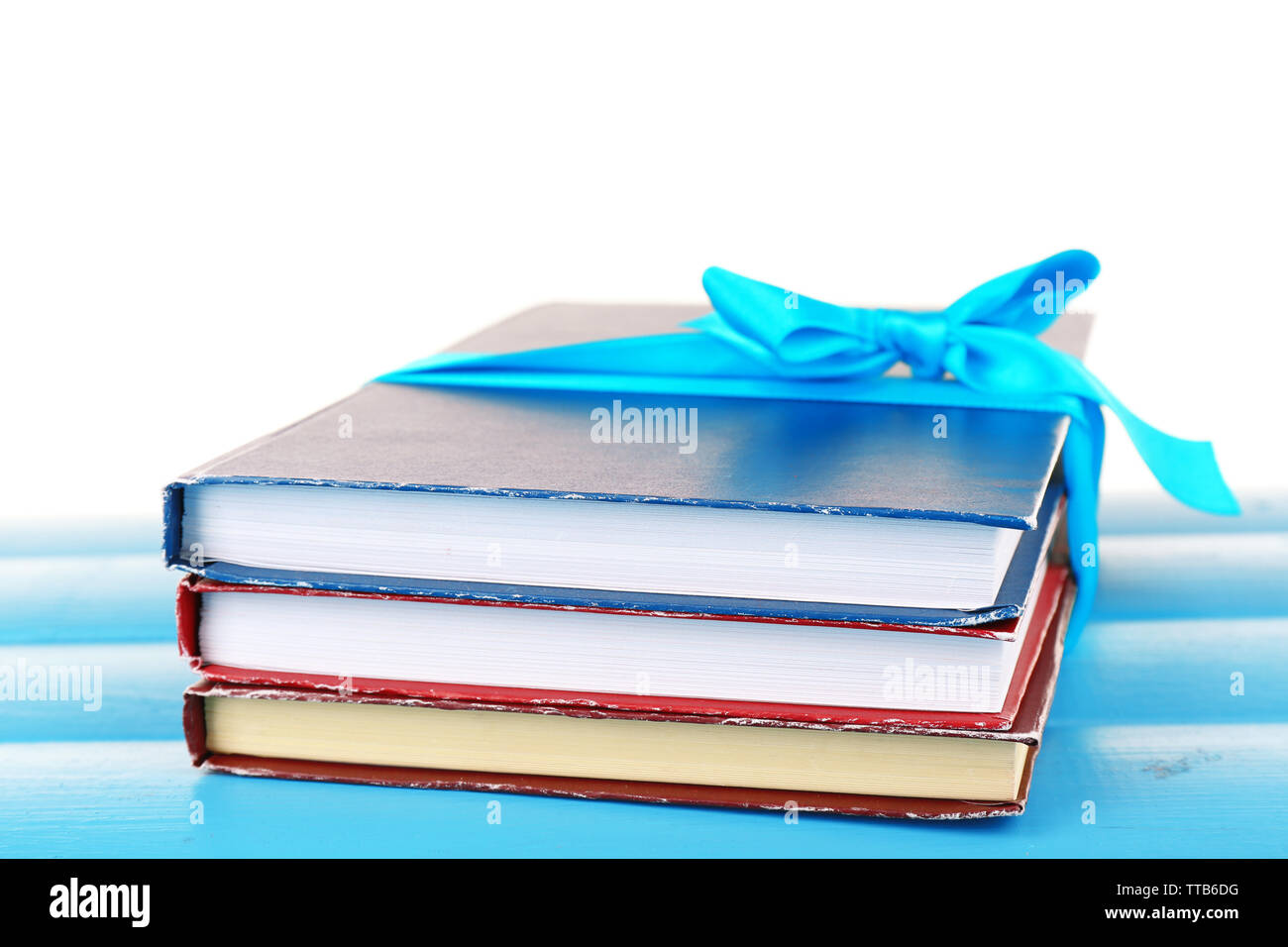 Stack of books with ribbon on table isolated on white Stock Photo - Alamy