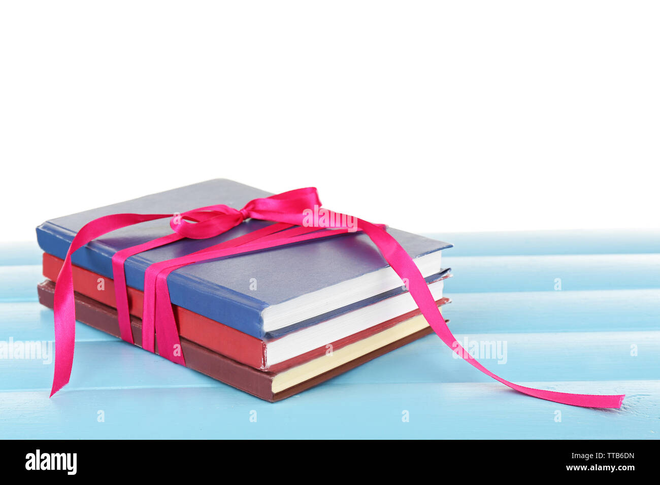 Stack of books with ribbon on table isolated on white Stock Photo - Alamy