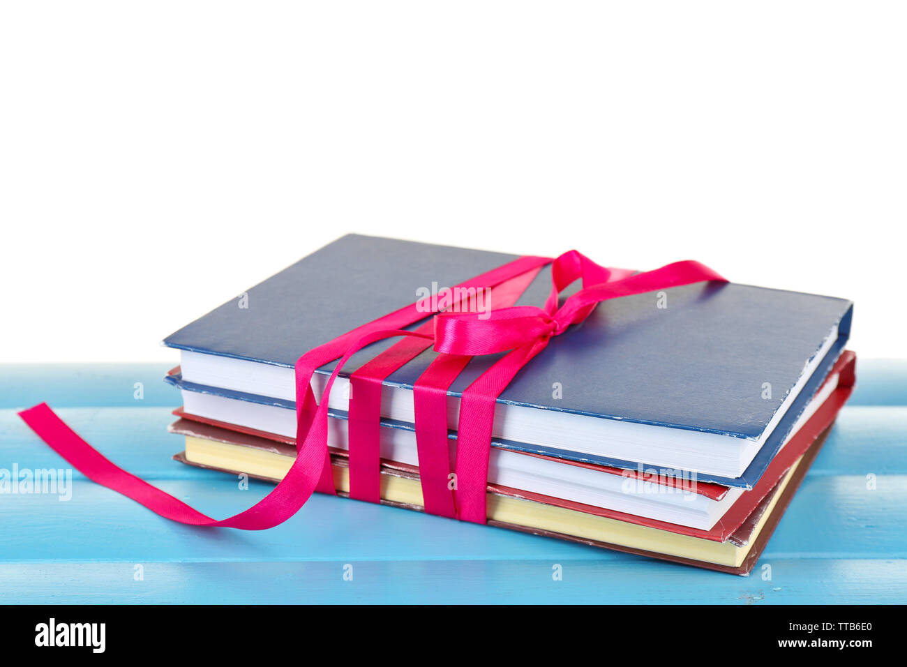 Stack of books with ribbon on table isolated on white Stock Photo - Alamy