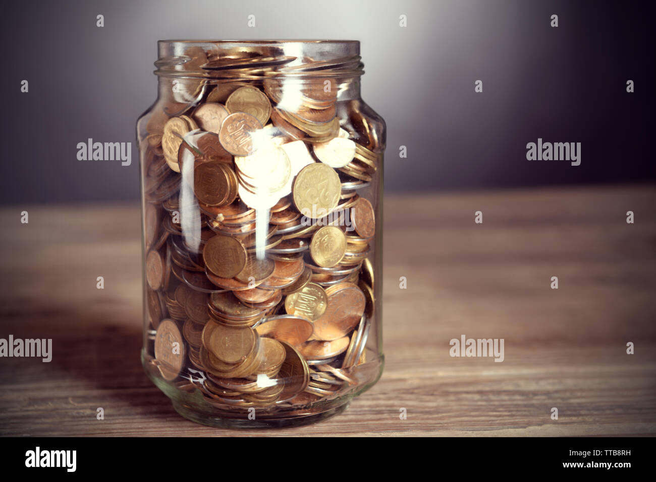 Coins in money jar on gray background Stock Photo - Alamy