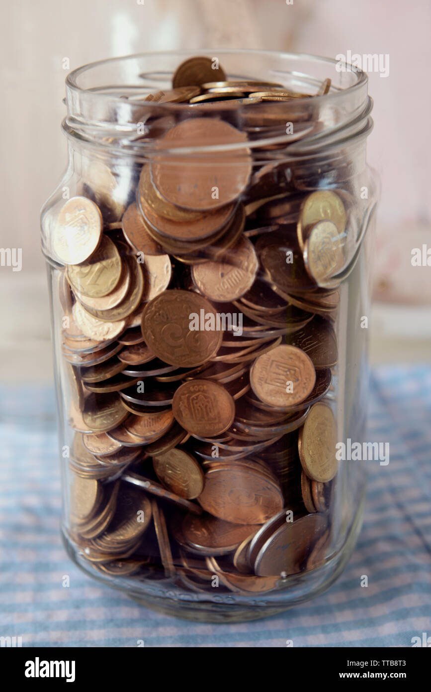 Coins in money jar on table close up Stock Photo - Alamy