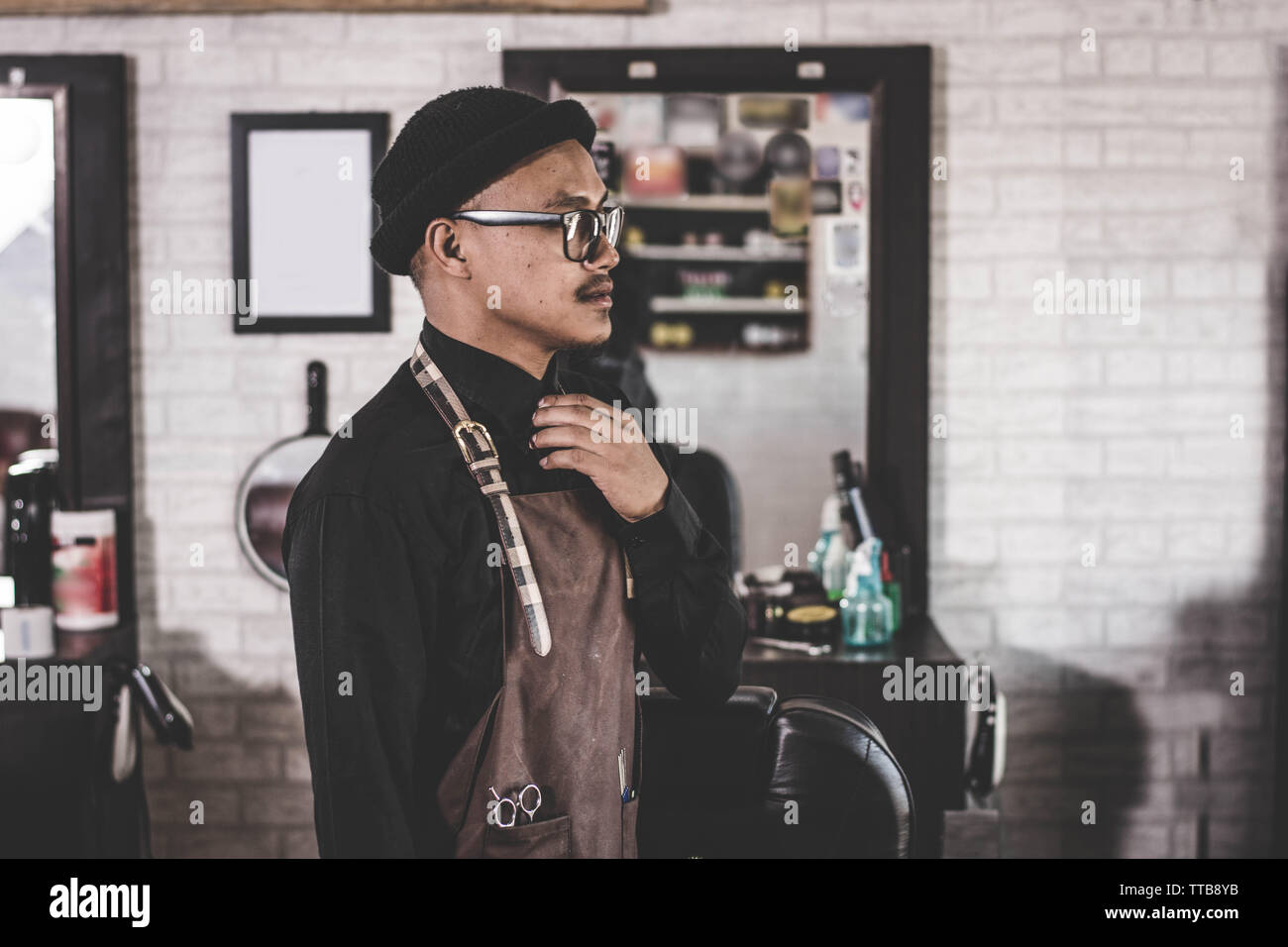 Barber man hairstylist posing and standing with apron crossed his arm ...