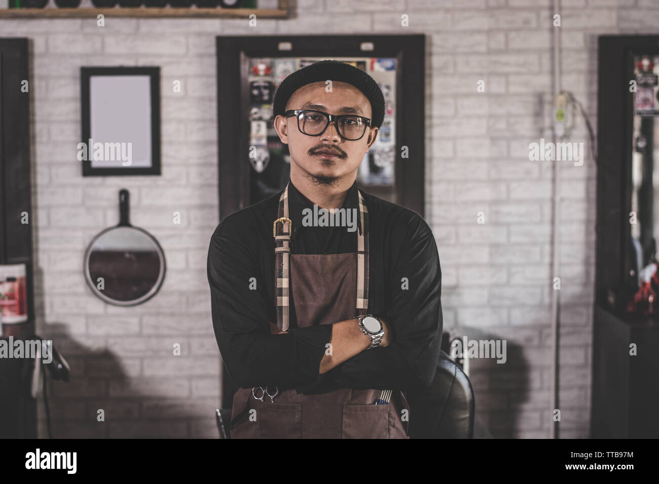 Barber man hairstylist posing and standing with apron crossed his arm ...