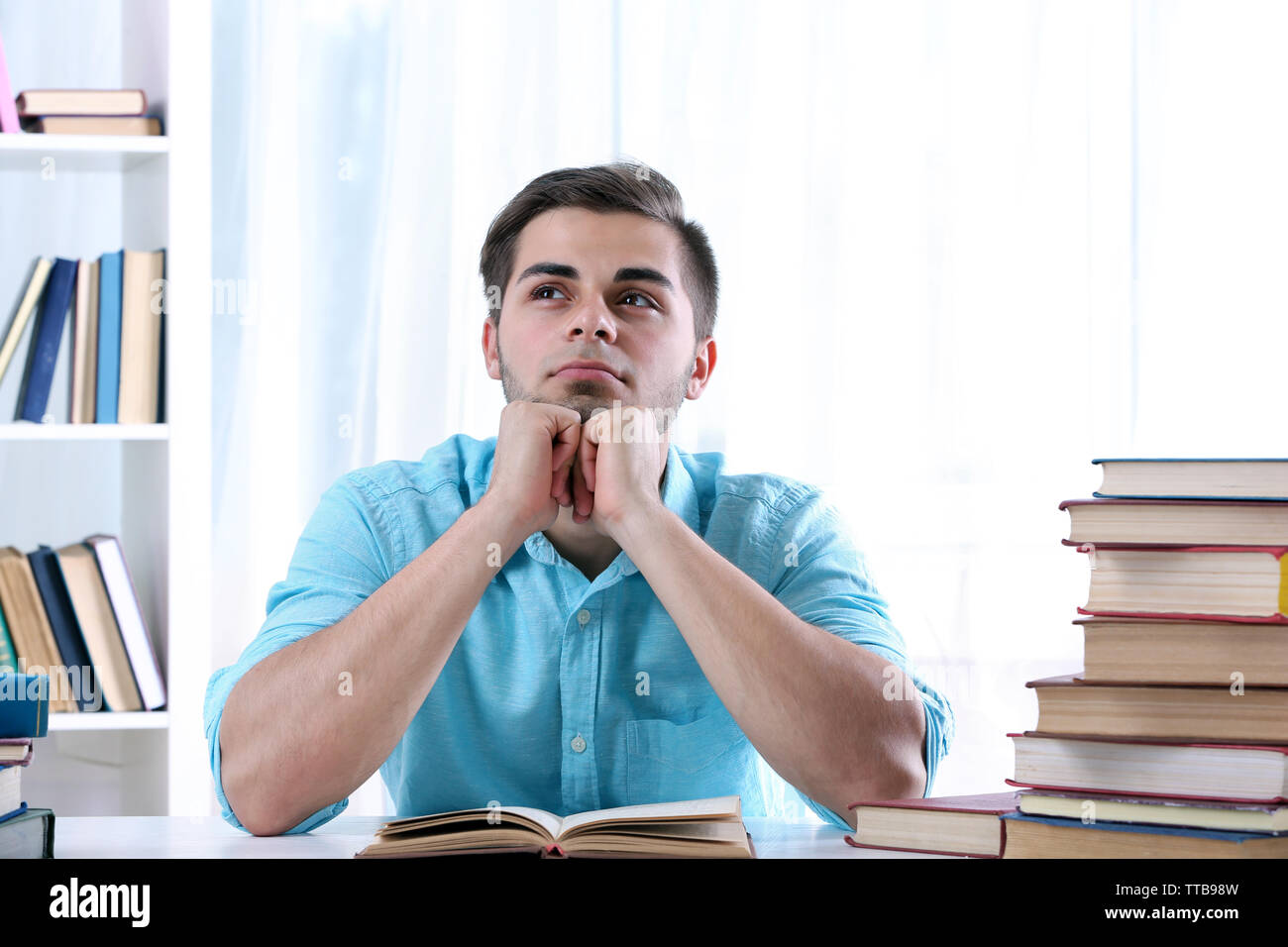 Young man reading book at table in room Stock Photo - Alamy