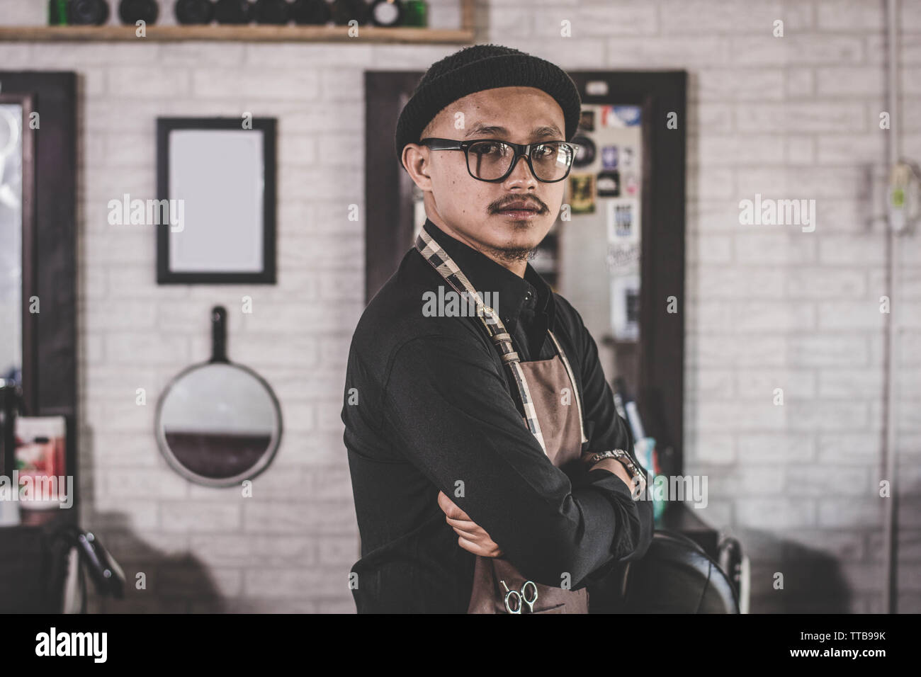 Barber man hairstylist posing and standing with apron crossed his arm ...
