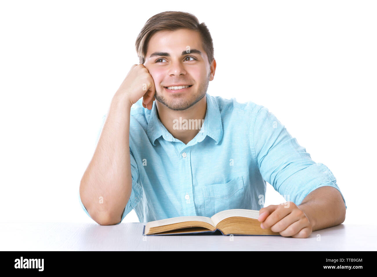 Young man reading book at table on white background Stock Photo - Alamy