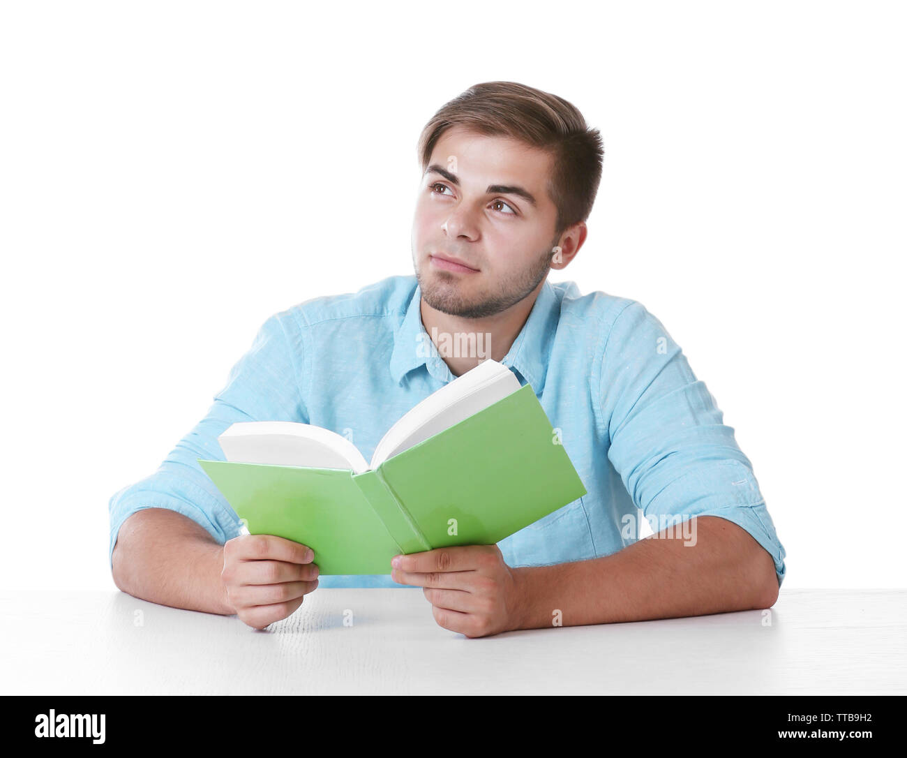 Young man reading book at table on white background Stock Photo - Alamy