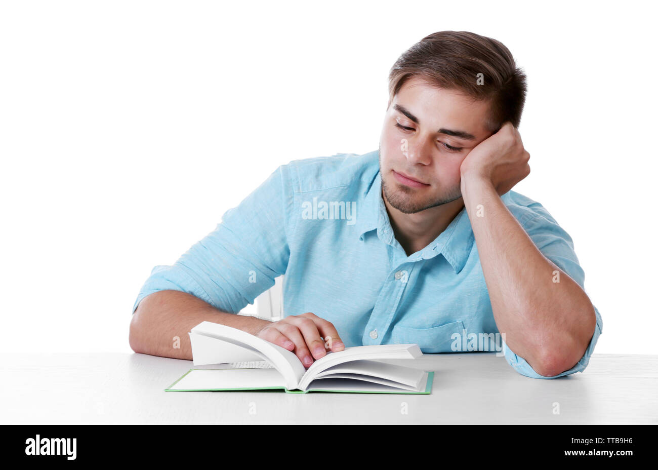 Young man reading book at table on white background Stock Photo - Alamy