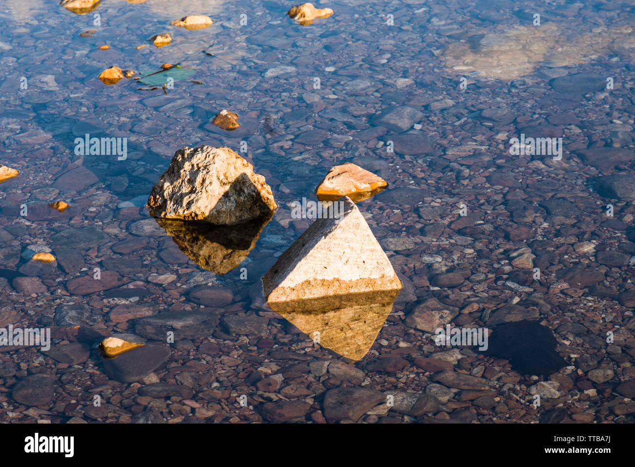 Rocks reflecting on still water Stock Photo - Alamy