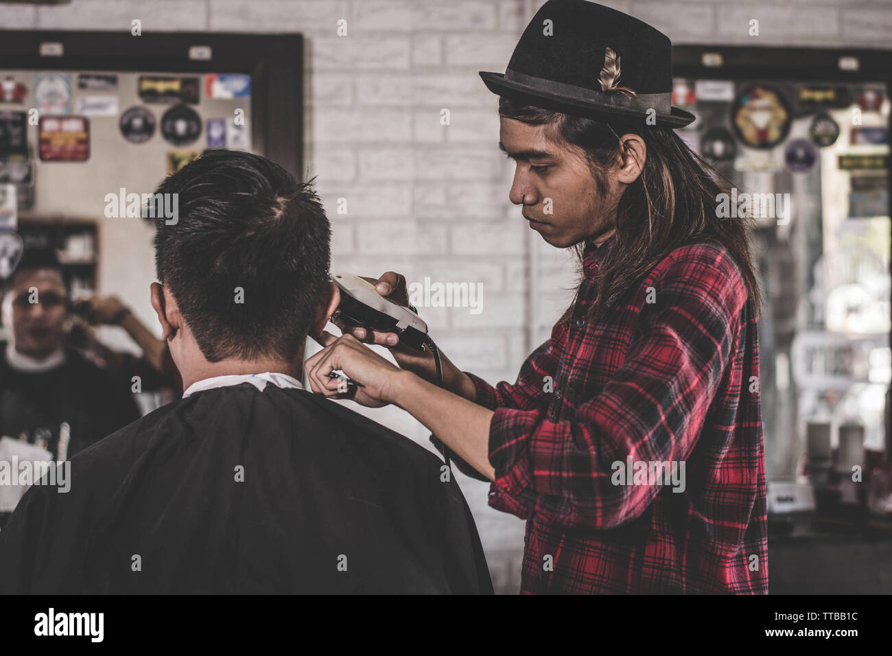 portrait of professional Asian man with long brown hair work as barber ...