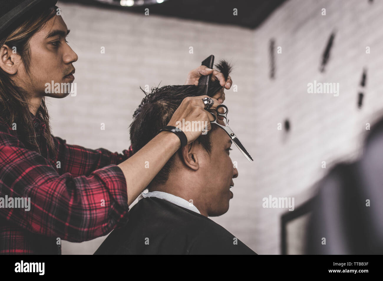 portrait of professional Asian man with long brown hair work as barber ...