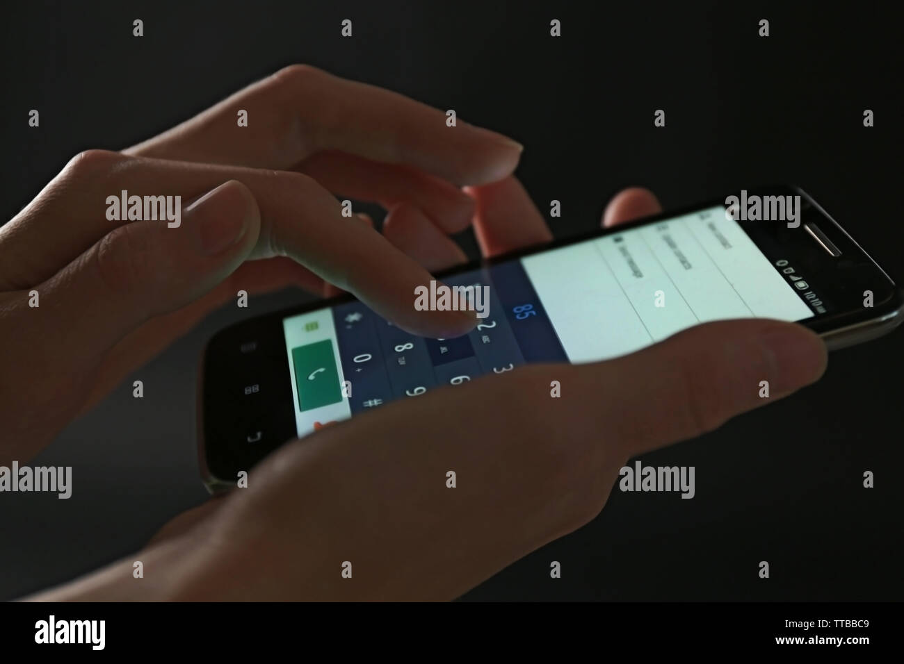 Finger touch number on smartphone to make a call on black background ...