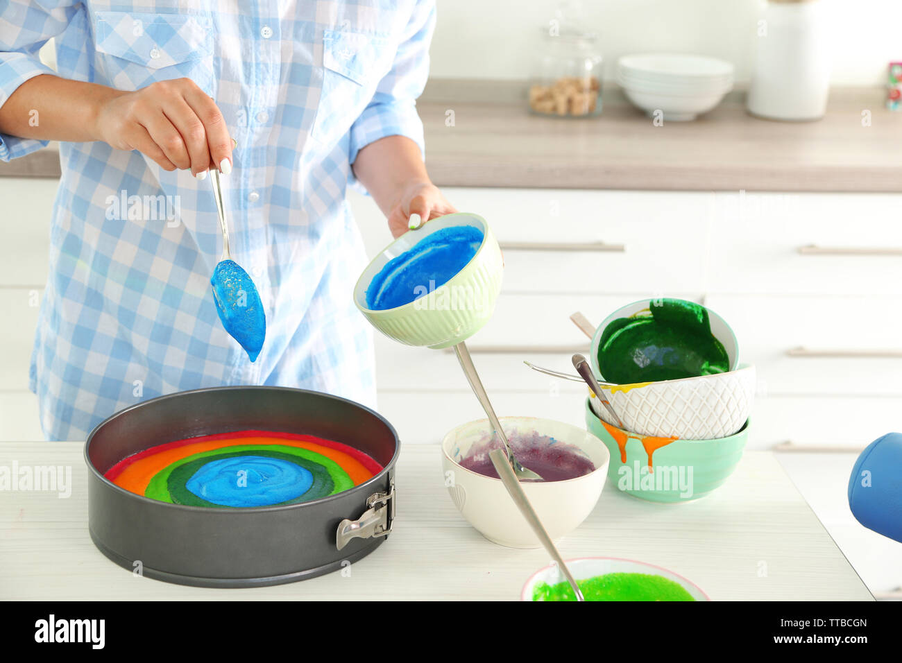 Young woman making rainbow cake in kitchen Stock Photo - Alamy