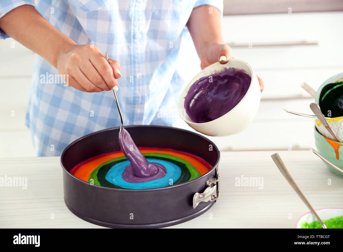 Young woman making rainbow cake in kitchen Stock Photo - Alamy
