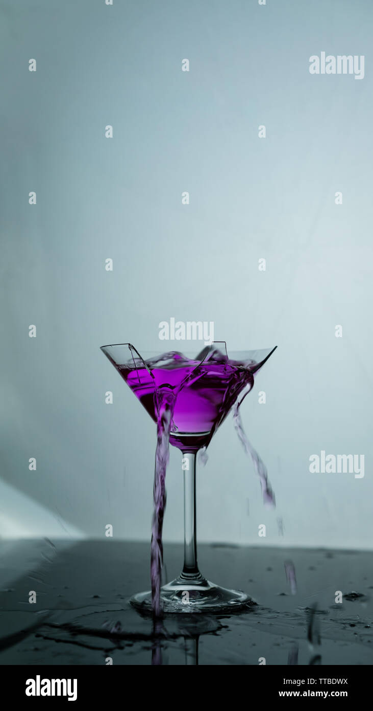glass cup breaking in slow motion with an ice and liquid of purple ...