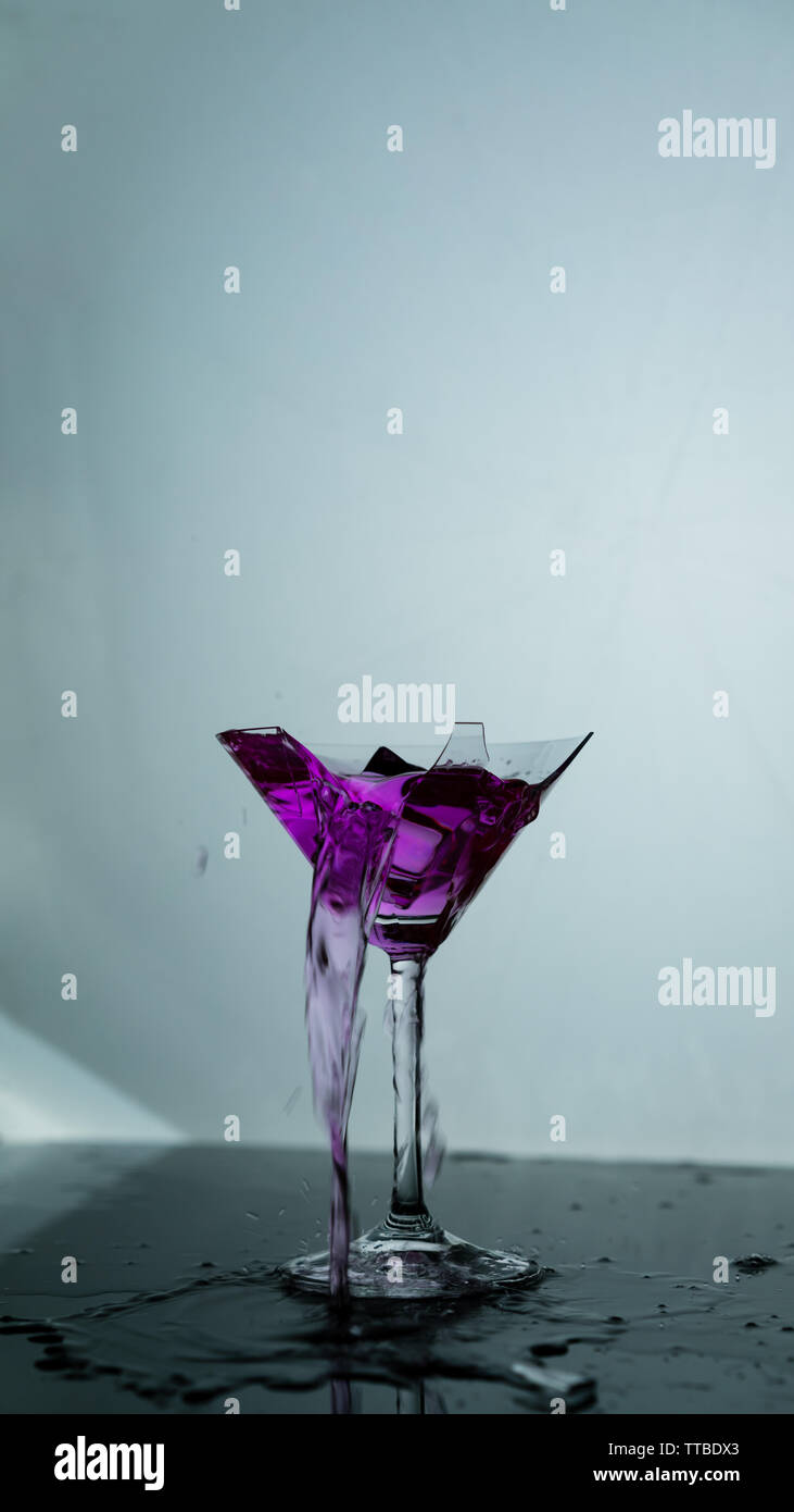 glass cup breaking in slow motion with an ice and liquid of purple ...