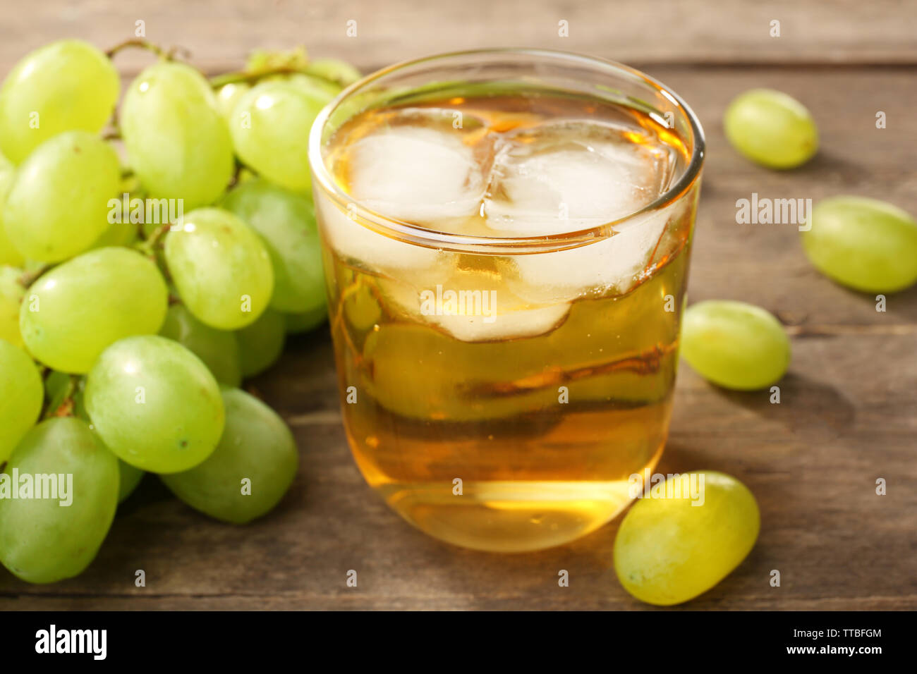 Glass of grape juice with ice cubes on wooden table, closeup Stock ...