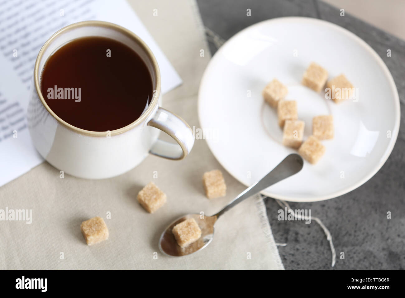 Cup of flavored coffee with lump sugar on table with napkin and ...
