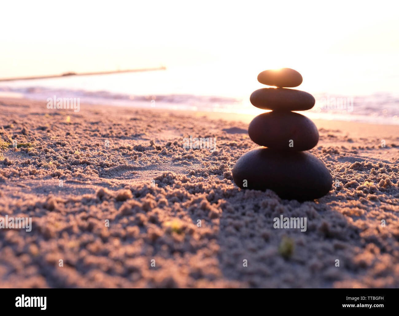 Stones pyramid on the beach at sunset Stock Photo - Alamy