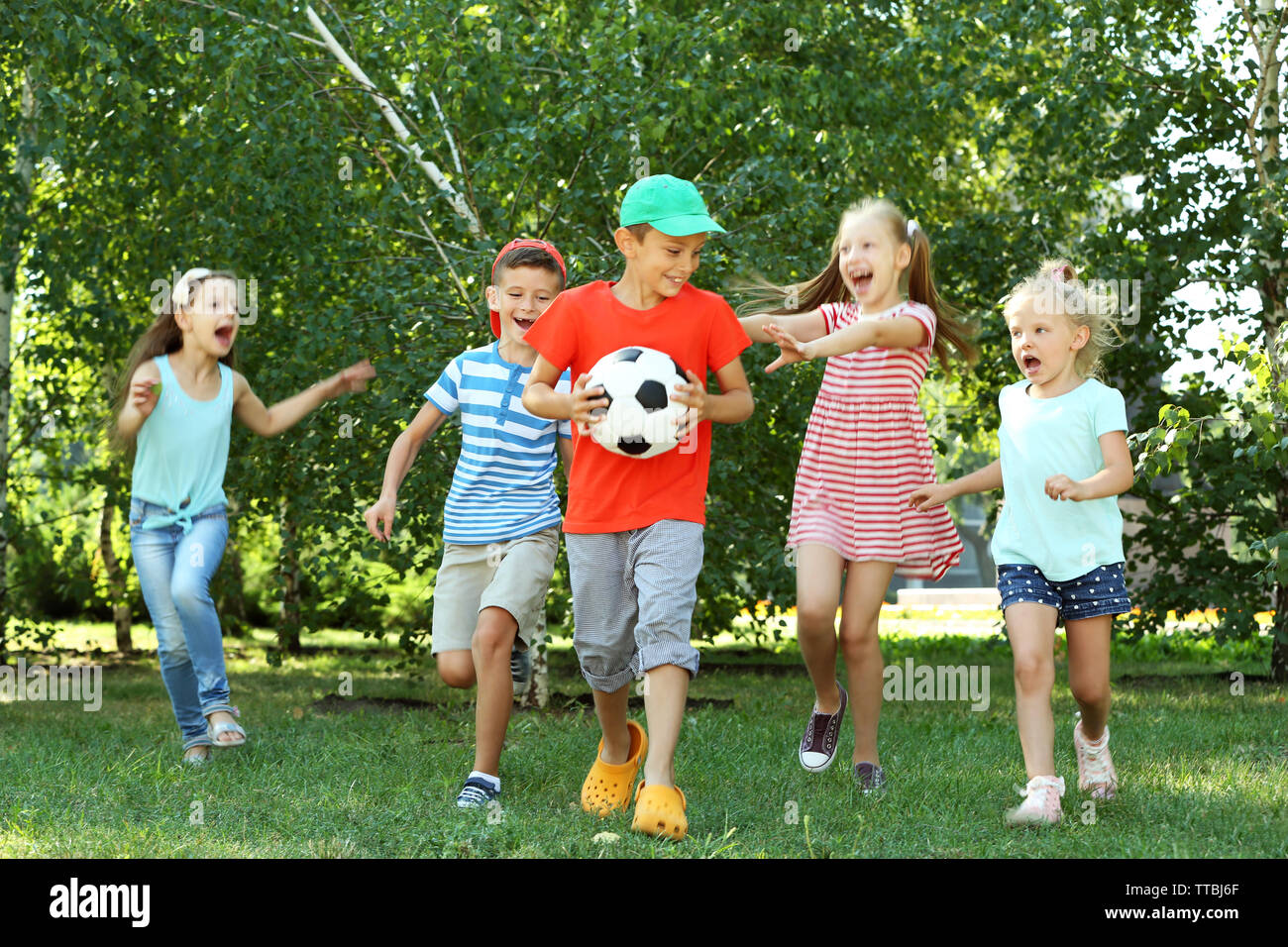 Happy active children playing with football in park Stock Photo - Alamy