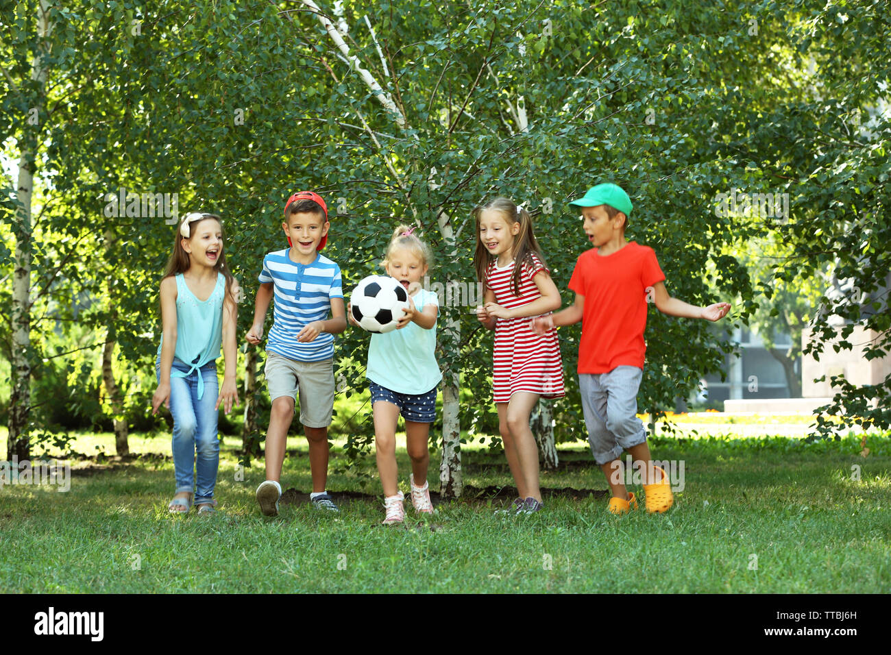 Happy active children playing with football in park Stock Photo - Alamy