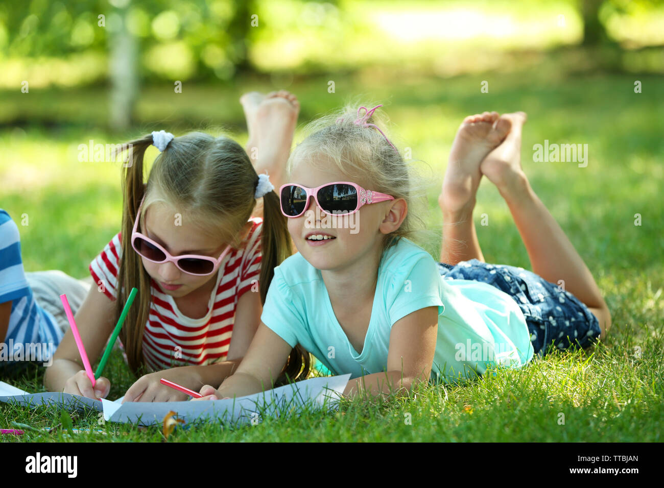Happy active children lying on green grass and drawing in park Stock ...