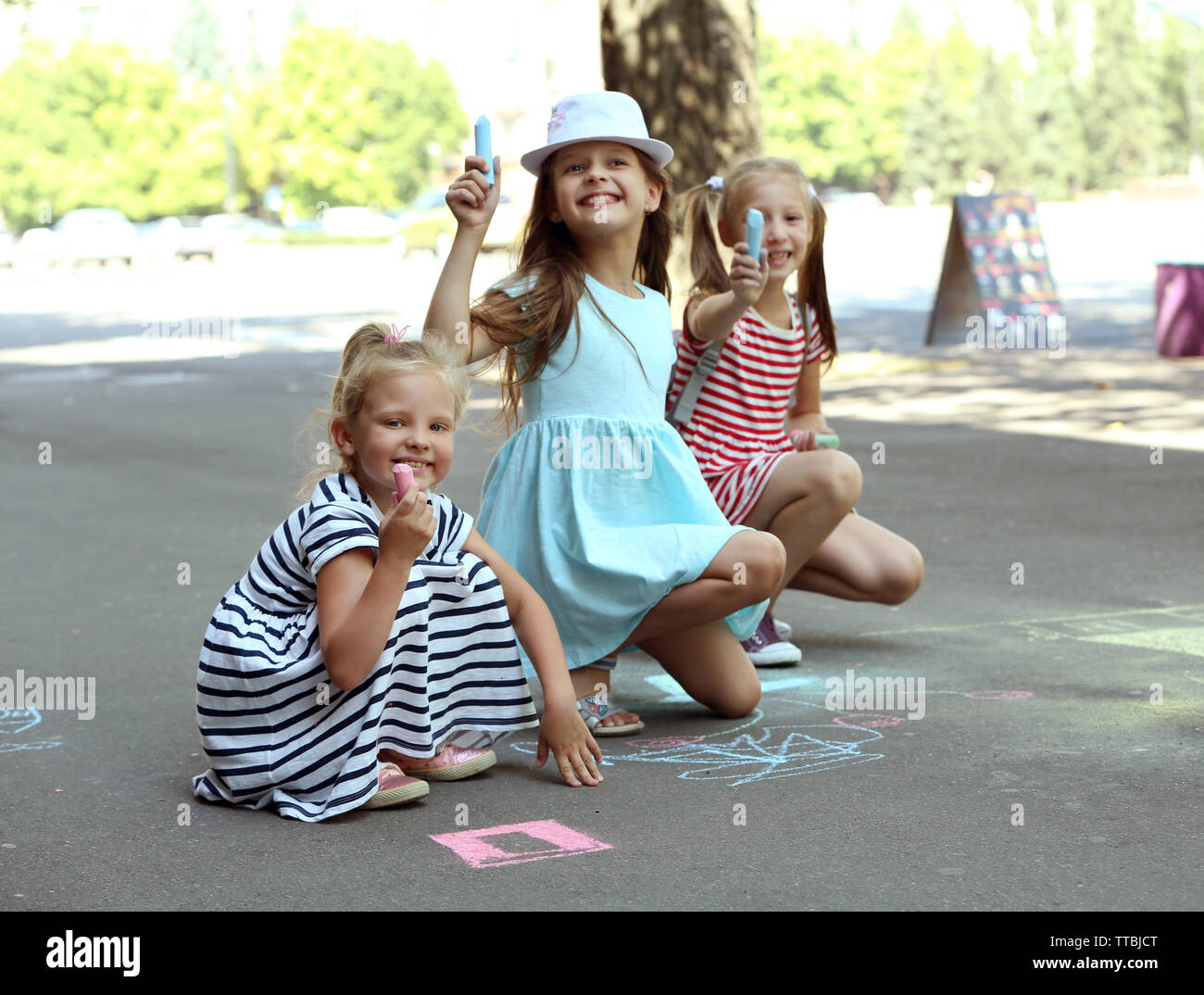 Happy active children drawing with chalk on asphalt Stock Photo - Alamy