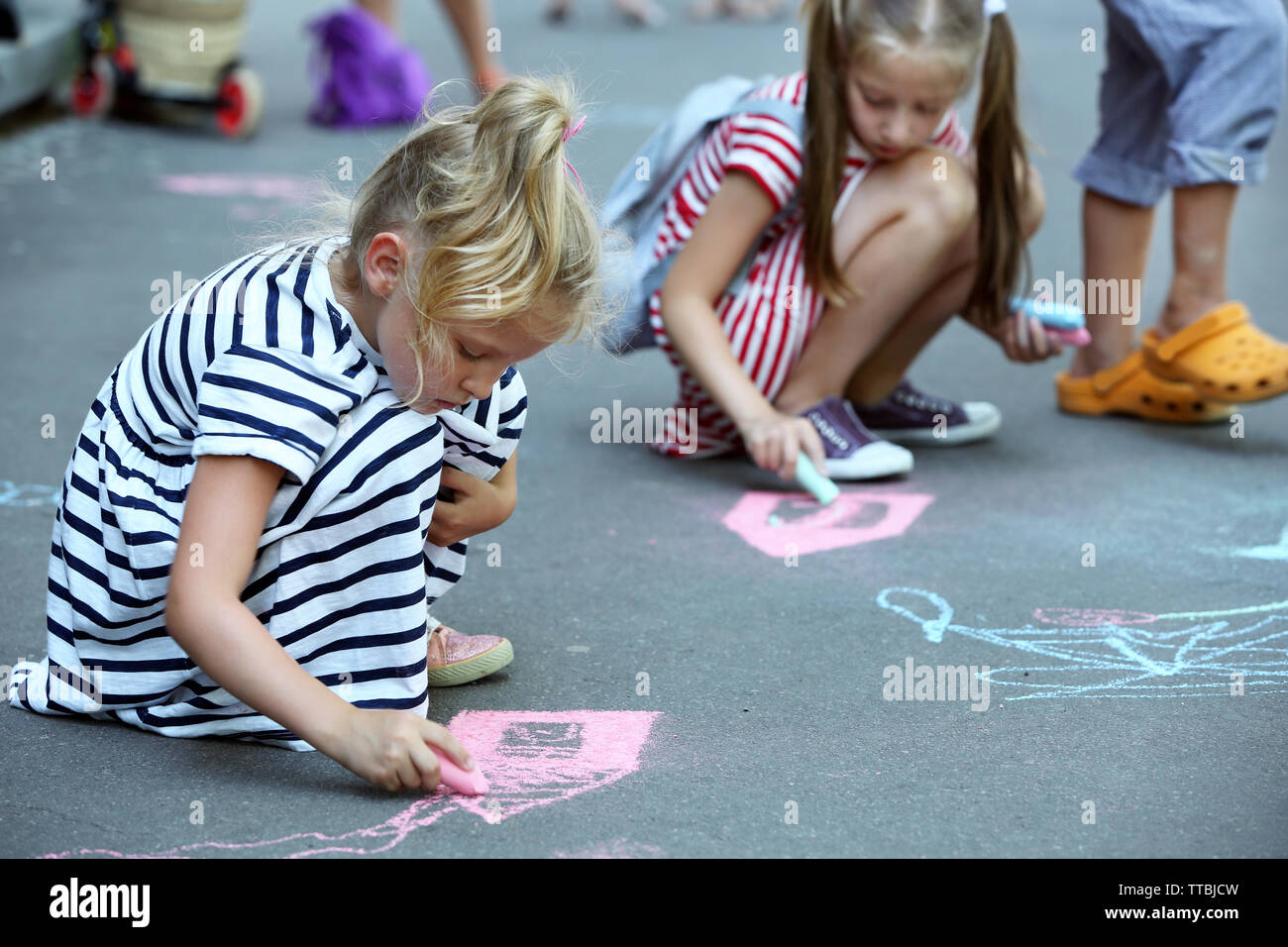 Happy active children drawing with chalk on asphalt Stock Photo - Alamy