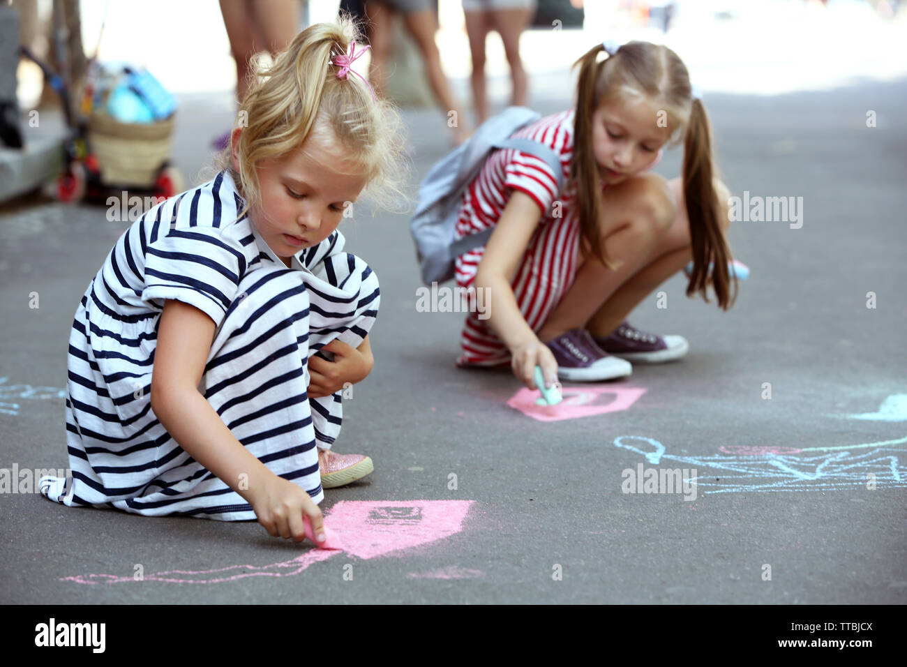 Happy active children drawing with chalk on asphalt Stock Photo - Alamy