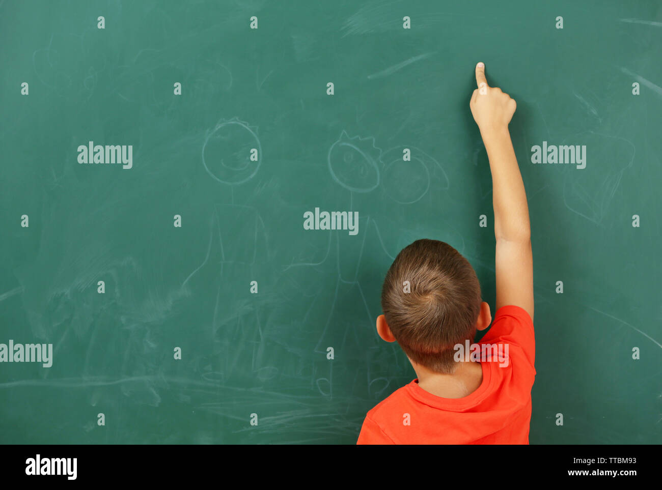 Little boy pointing at something at black chalkboard in classroom Stock ...
