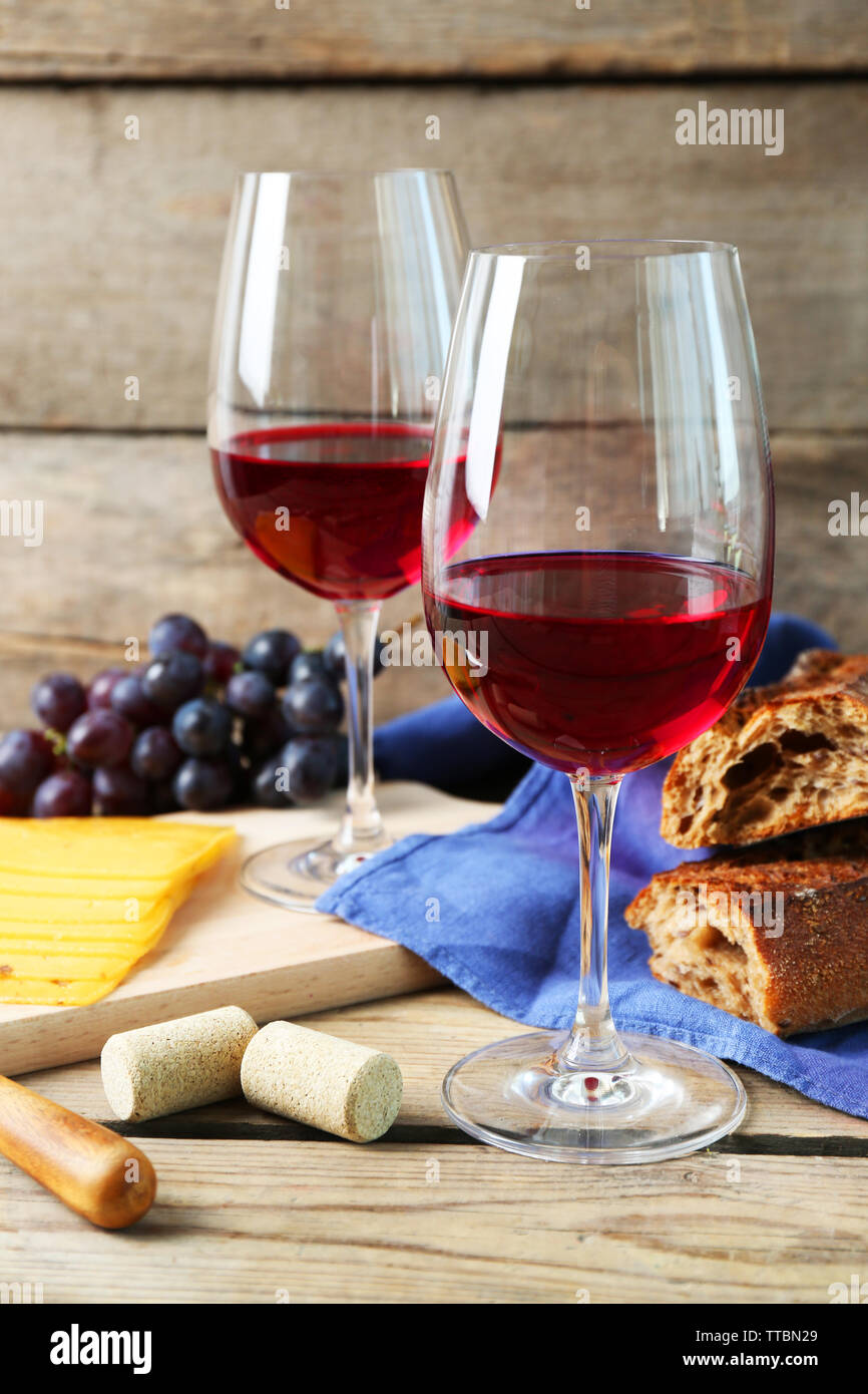 Still life of wine, grape, cheese and bread on rustic wooden background ...