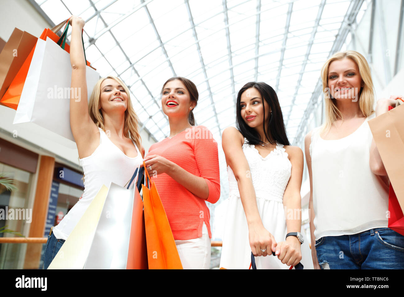Happy girls with shopping bags in mall having fun Stock Photo - Alamy