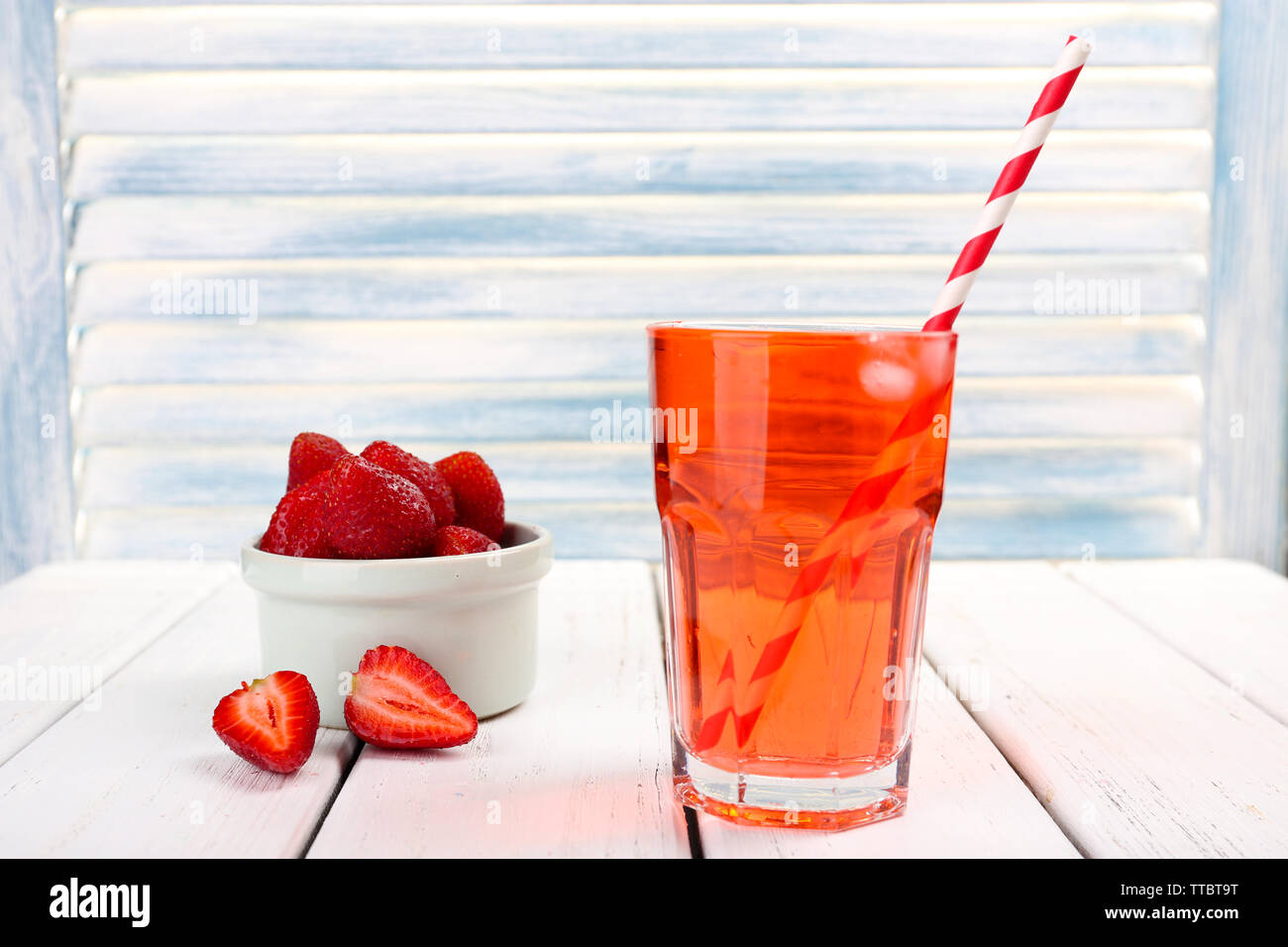 Strawberry cocktail and strawberries in bowl on wooden table on light ...