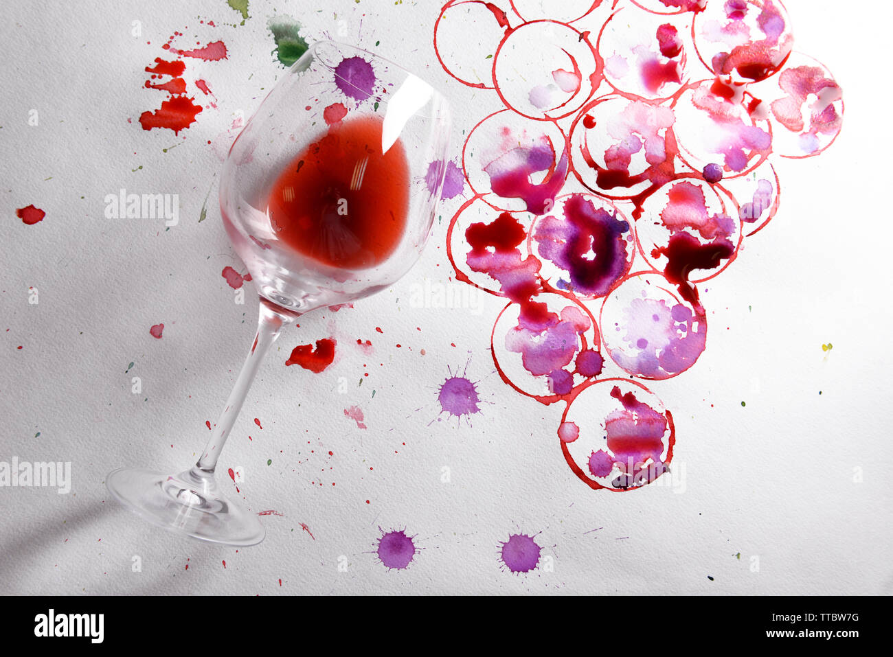 Wineglass of spilled wine with watercolors stains on paper background ...