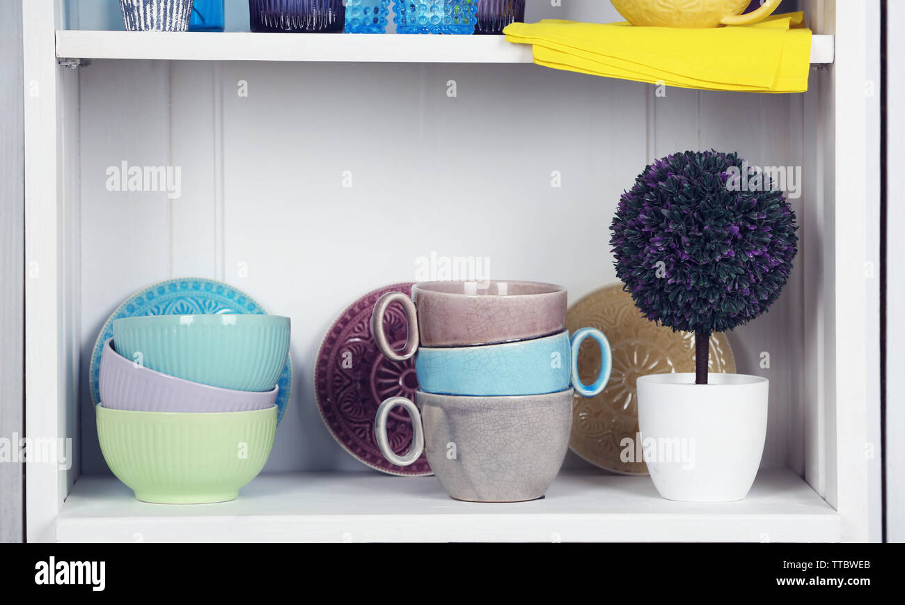 Clean glasses, plates and cutlery on shelf in kitchen cupboard Stock ...