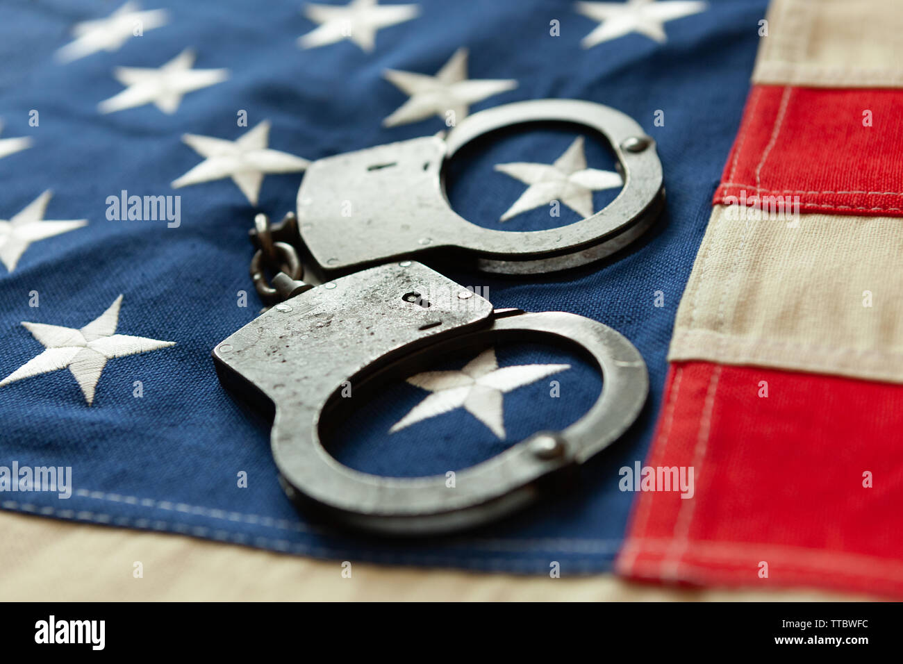 Metal handcuffs over an old USA flag - studio shot Stock Photo - Alamy