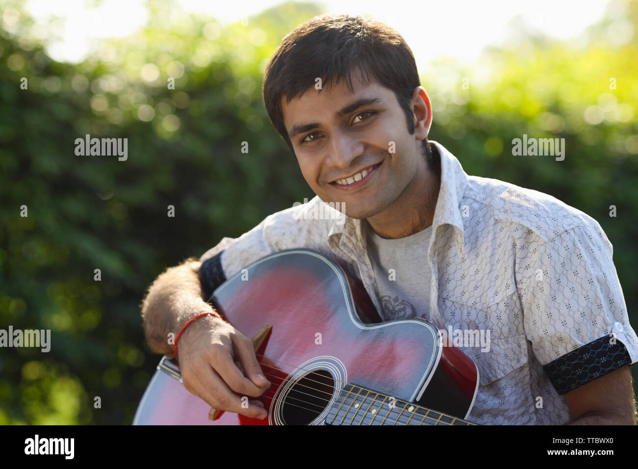 Man playing a guitar and smiling Stock Photo - Alamy