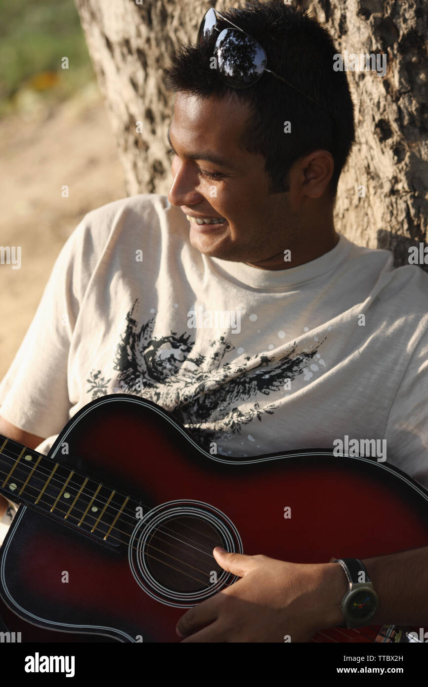 Man playing a guitar and smiling Stock Photo - Alamy