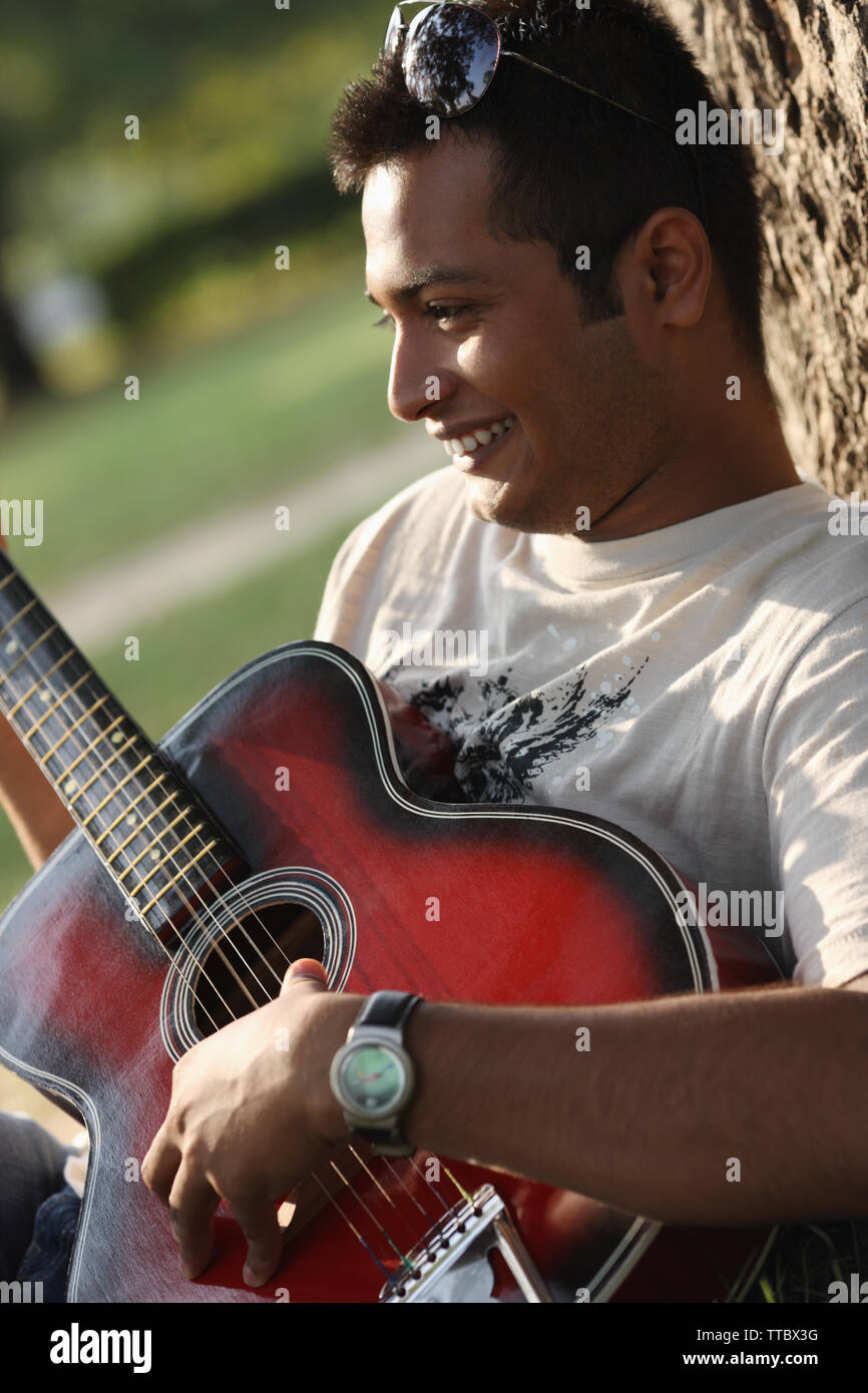 Man playing a guitar and smiling Stock Photo - Alamy