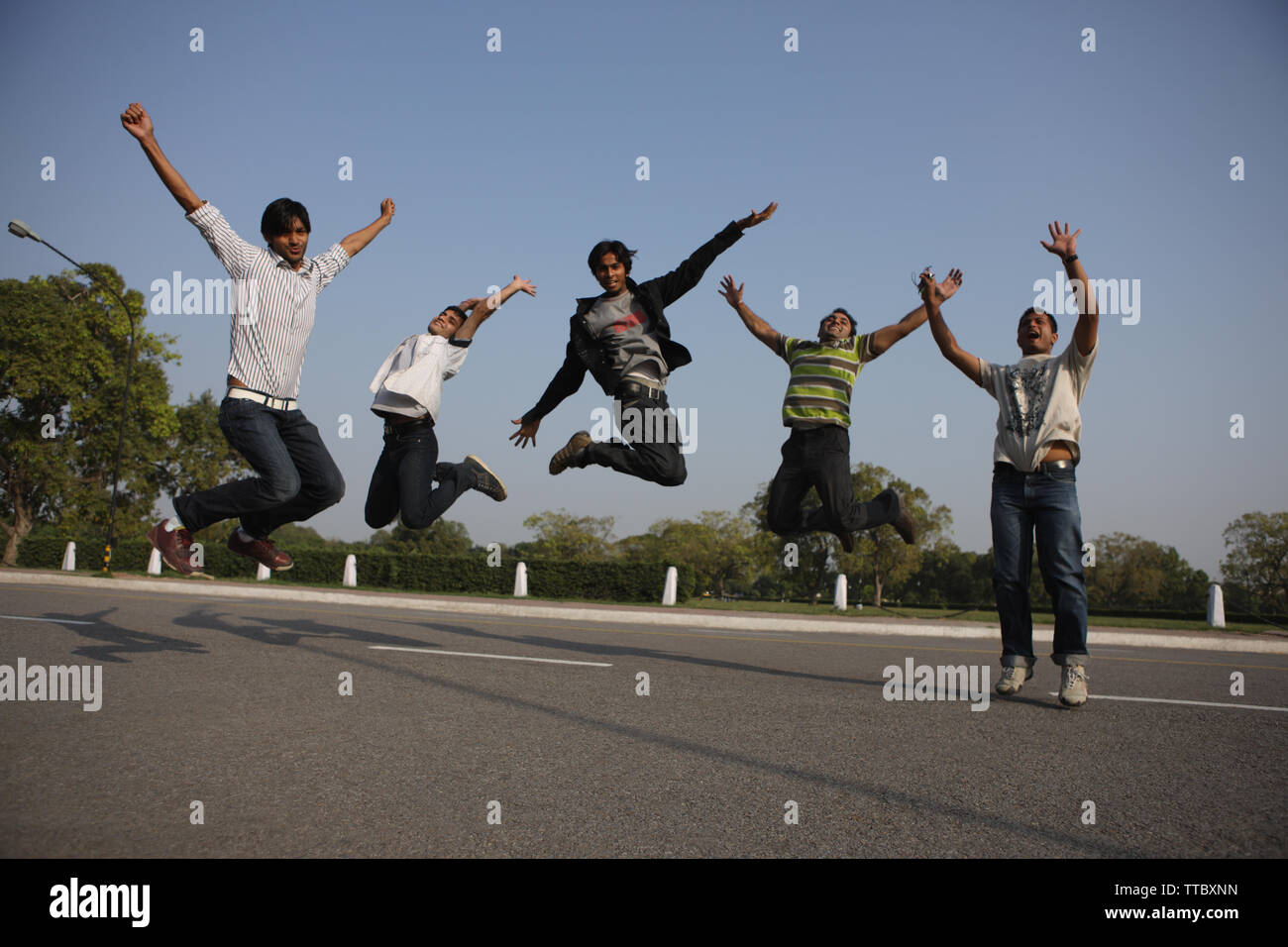 Friends jumping on the road Stock Photo - Alamy