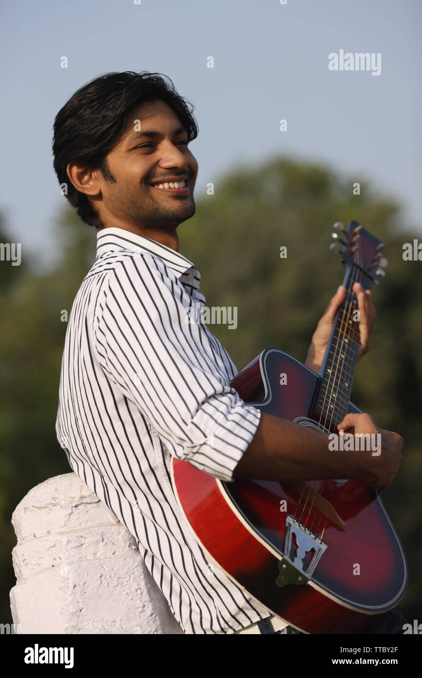 Man playing a guitar and smiling Stock Photo - Alamy