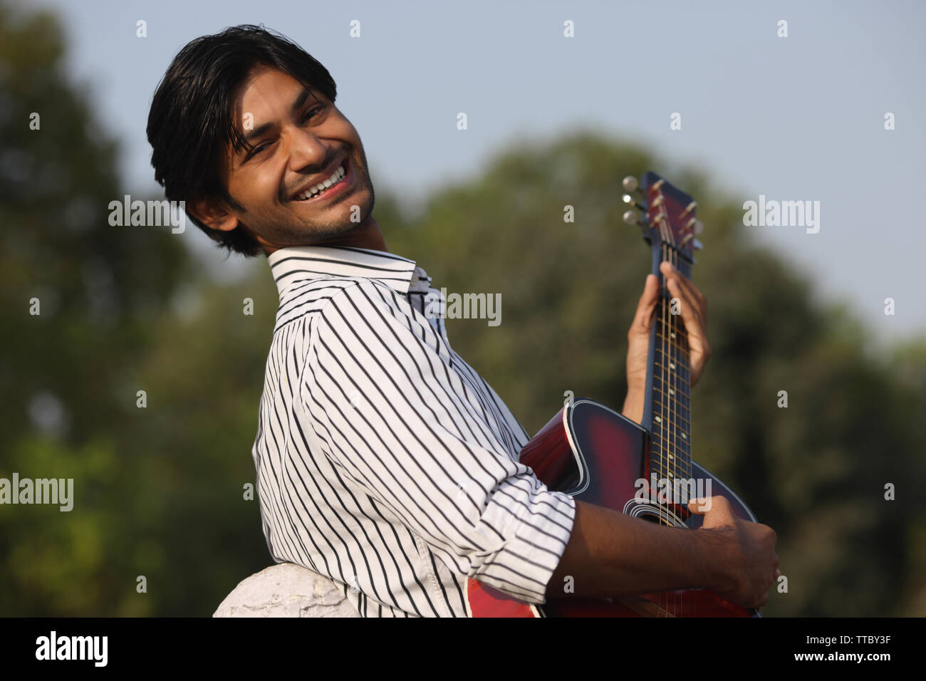 Man playing a guitar and smiling Stock Photo - Alamy